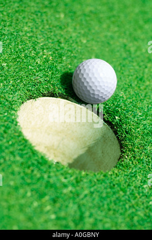 Golf ball on the edge of hole Stock Photo - Alamy