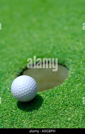 Golf ball on the edge of hole Stock Photo - Alamy