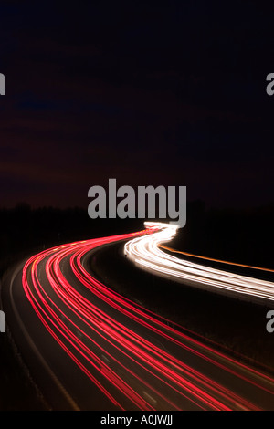 At night, white car headlights create streaks along a town centre road ...