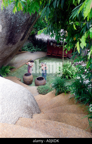 Two ladies in sarongs soak themselves using pots of water in the ...