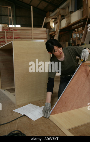 Young woman measuring sheet of plywood with tape measure Stock Photo ...
