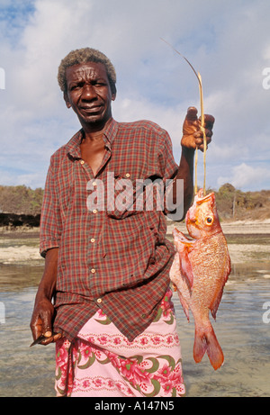 Africa, Kenya, Malindi. Kenyan man holding tropical fish caught in the ...