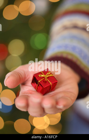 Woman with Christmas tree holding gift on blue background Stock Photo ...