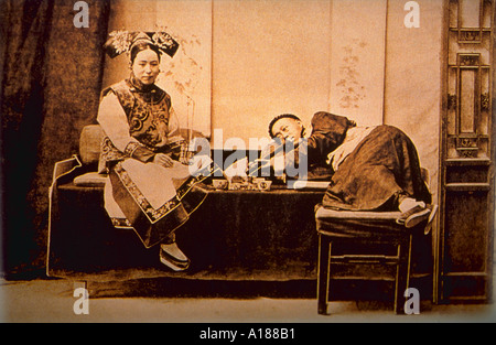 An old Chinese woman smoking an Opium pipe outside the gates of a ...