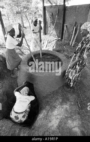 B/W of members of a women's cooperative pottery loading a kiln with ...