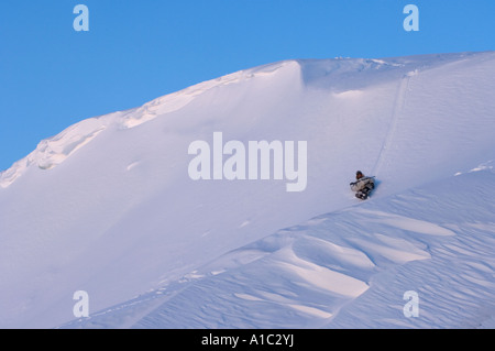 inupiat hunter sleds down a snow bank on his back Herschel Island Yukon ...