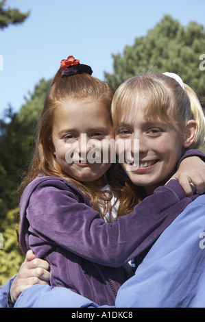 Two Smiling Girls With Arms Wrapped Around Legs Stock Photo - Alamy