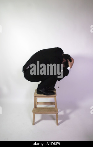 Business man crouched on a stool looking angry and stressed Stock Photo ...