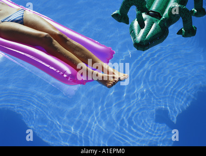 Woman relaxes on blue raft in pool while enjoying sunny day surrounded ...