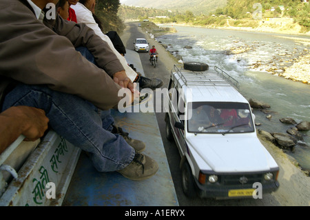 Passengers travelling on roof of overfull bus meeting another bus ...