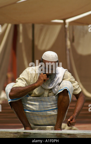 Old religious Muslim man performing ritual bath in Jama Masjid mosque ...