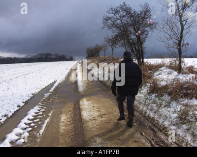 A woman wrapped up against the cold walking along the shoreline on ...