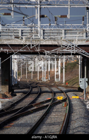 Railroad track and over head cables seen from a pavement behind a fence ...