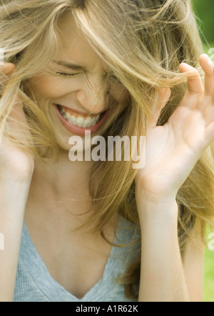 Young woman sniggering or giggling into her hand in a close up cropped ...