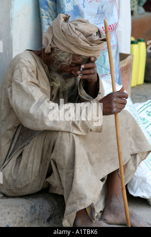Homeless man in ragged clothes eating a meal standing as his benefactor ...