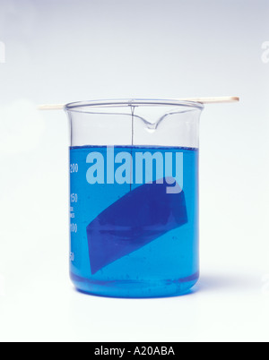 Blue copper sulfate solution in a conical flask on a laboratory bench ...