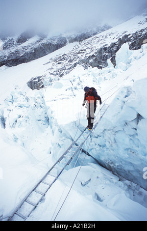 A climber on Mount Everest crossing a crevasse on a ladder in the ...
