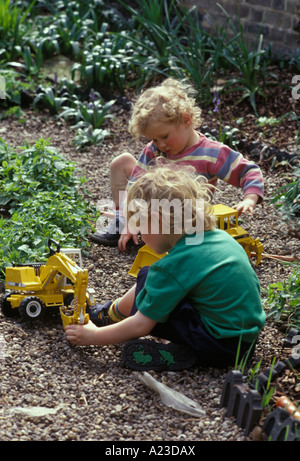 Children playing with trucks and diggers in outdoor sandbox in winter ...