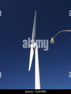 Standing single white turbine tower rising over grassland at mountain ...