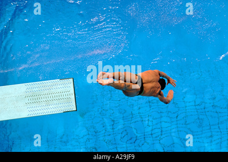 Overhead view of a male springboard diver forming a crucifix shape as ...