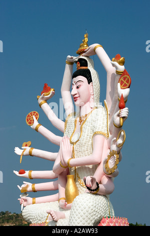 A huge statue of a multi armed Buddha sits on a hill near to the city ...