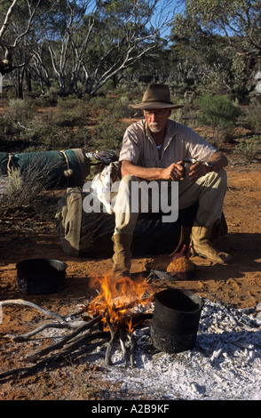Men and dog sitting next to campfire Stock Photo - Alamy