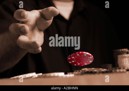 Man throwing chips into pot at card table Stock Photo - Alamy