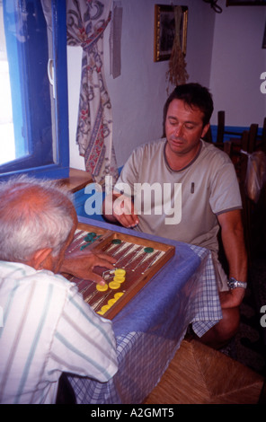 Two seated Greek men playing backgammon, faded blue door behind ...