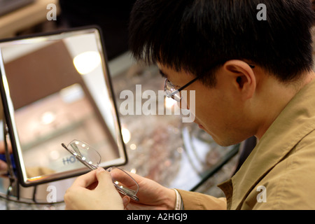 Young asian man in eyeglasses and black T-shirt leaning on table ...