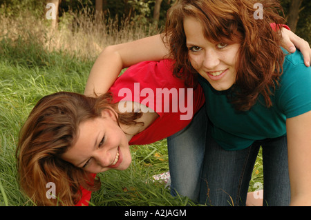 Young women laughing and frolicking together pulling each other's hair ...
