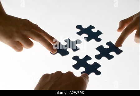 Hands working together to build a jigsaw Stock Photo - Alamy