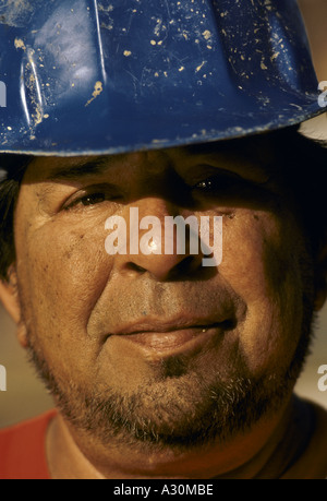 A construction worker wearing a hard hat and safety harness is securing ...