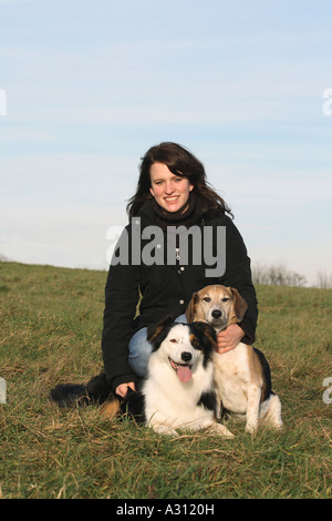 Young woman and her Australian Shepherd outside by a campfire. Reading ...
