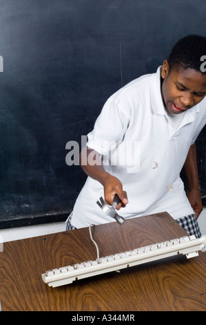 young boy breaking computer keyboard with a hammer Stock Photo - Alamy