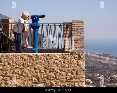 Tourist looking through a telescope towards the historic town centre ...