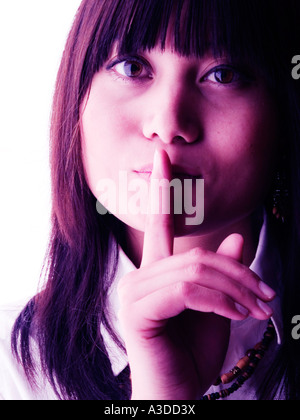 Young woman presses index finger over lips looks mysteriously on the ...