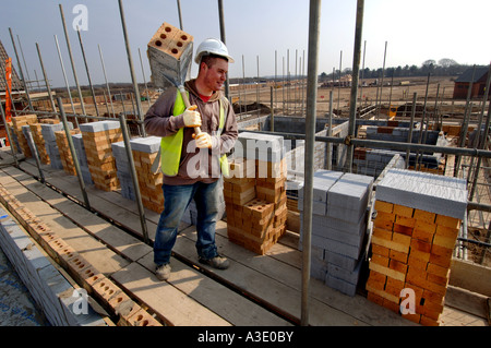 A young hod carrier worker on a building site with a load of bricks ...