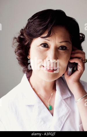 Asian female doctor talk phone call consult patient holding clipboard ...