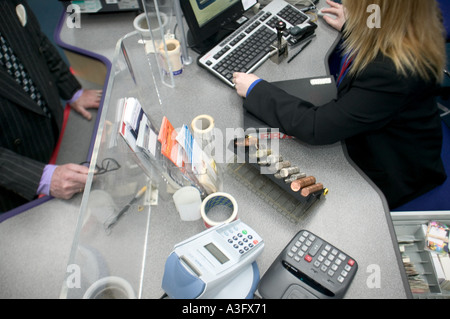 Post Office workers dealing with customers over the counter ...