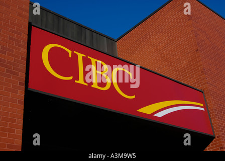 CIBC bank sign and logo against a brick building background and blue ...