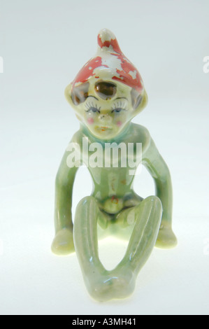 Antique ceramic pixie figurine in a red outfit sitting on a tree stump ...