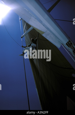 Man climbing the mast of a racing yacht (Imoca 60 class yacht Aviva at ...