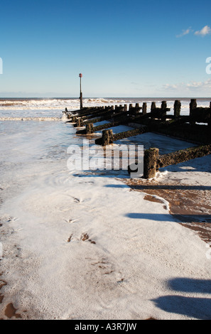 Wooden sea defences (breakwaters or groynes) with small wave, on the ...