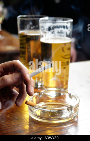 Smoking cigarette in a smoky pub with pint glasses of beer, UK Stock ...