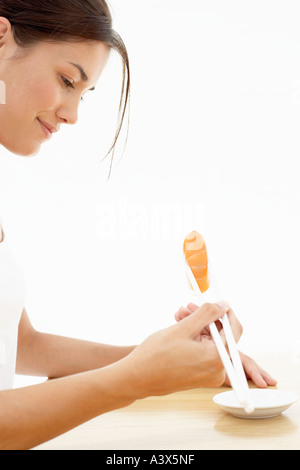 Young brunette woman eating sushi using chopsticks doing stop gesture ...
