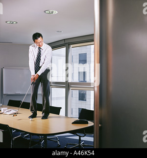 Businessman playing golf in office hallway Stock Photo - Alamy
