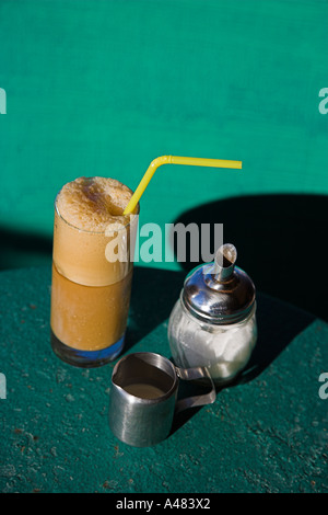 A vertical closeup of a refreshing iced coffee in a glass next to ...