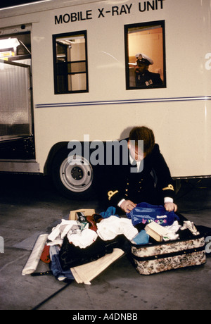 A customs officer searches incoming baggage, Stansted Airport Stock ...