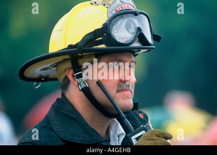 Male Firefighter holding radio in front of fire truck wearing bunker ...