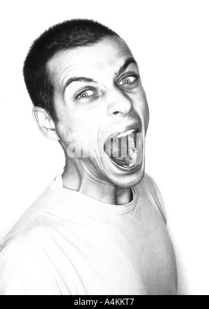 An young man yells at the camera with black t-shirt and grey background ...
